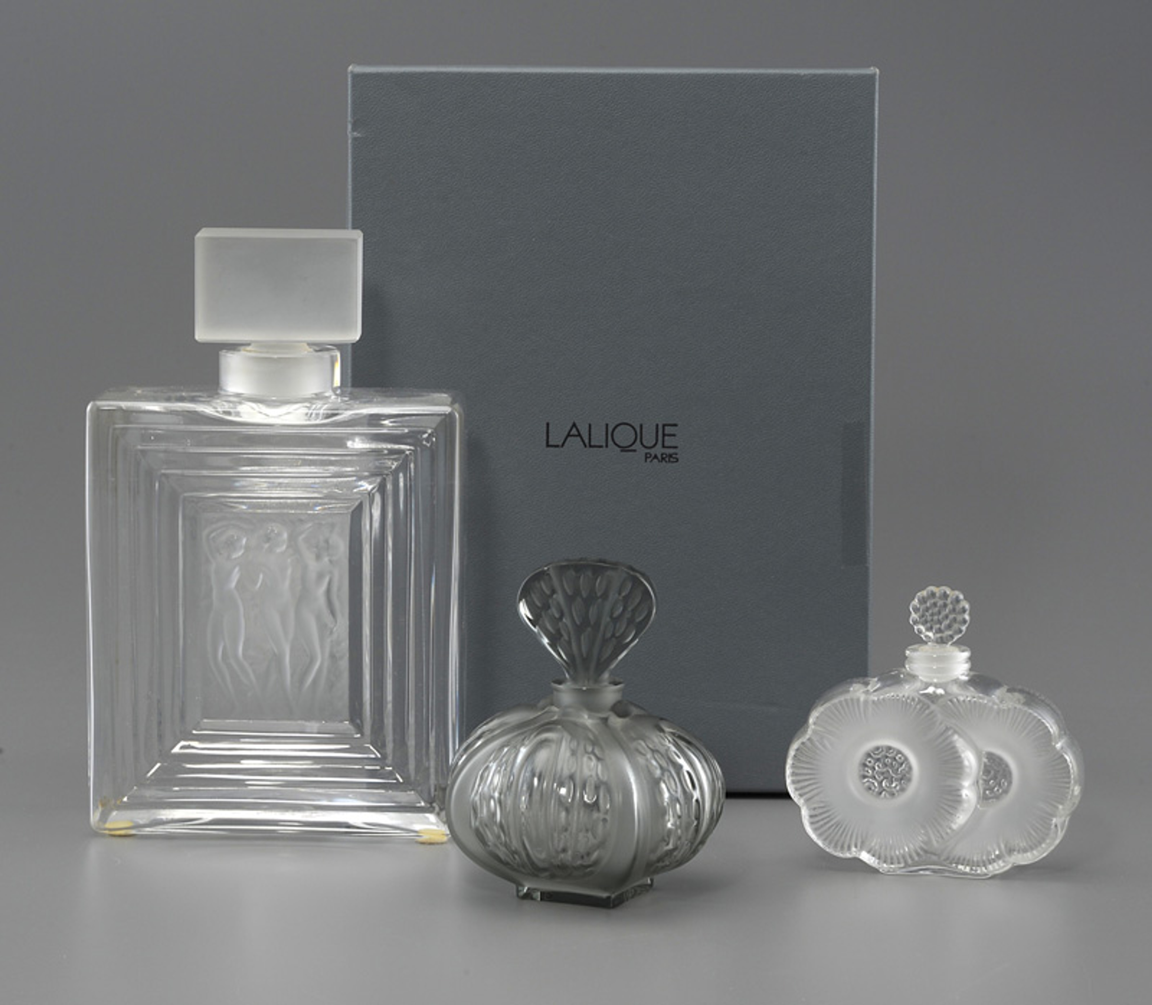 3 flacons en verre moulé signés Lalique: "Deux… | Piguet